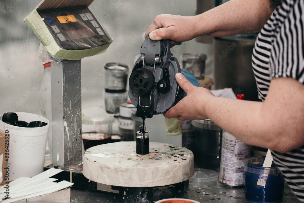 The painter’s hands are holding a can of paint on which a mix cover for ...