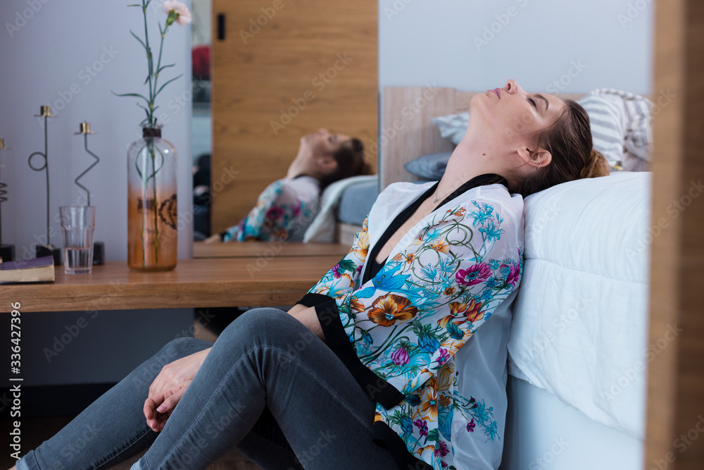 Extremly tired young woman sitting beside a bed, isolating alone at ...