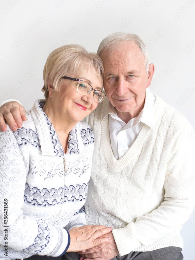 Beautiful elderly couple sit in an embrace looking at the camera on a ...