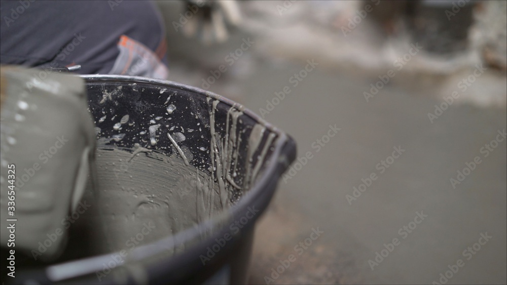 Hand mixes waterproofing mortar in a bucket. Male hand holding a brush ...