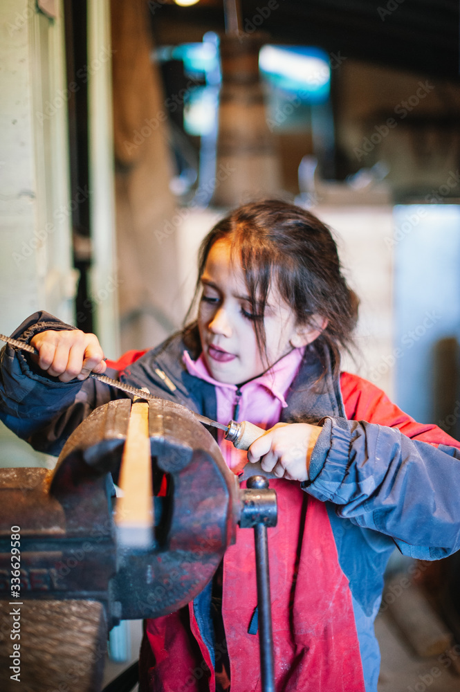 little girl works the wood -child performs crafts on wood in the home ...