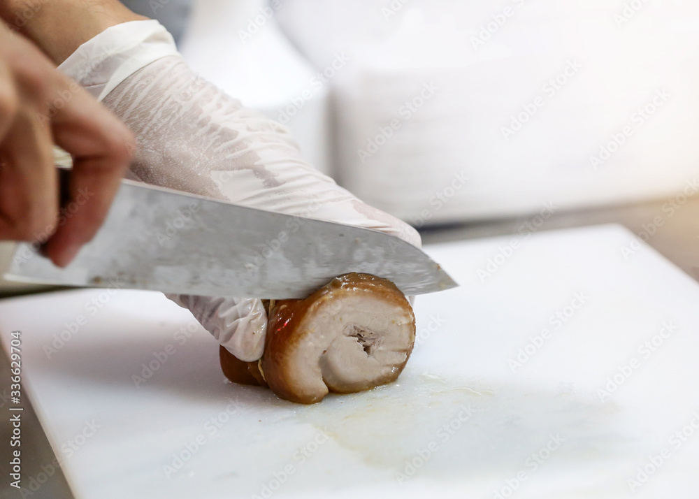 Chef in restaurant kitchen cutting meat, chef hands slicing belly pork ...