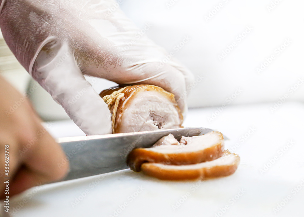 Chef in restaurant kitchen cutting meat, chef hands slicing belly pork ...
