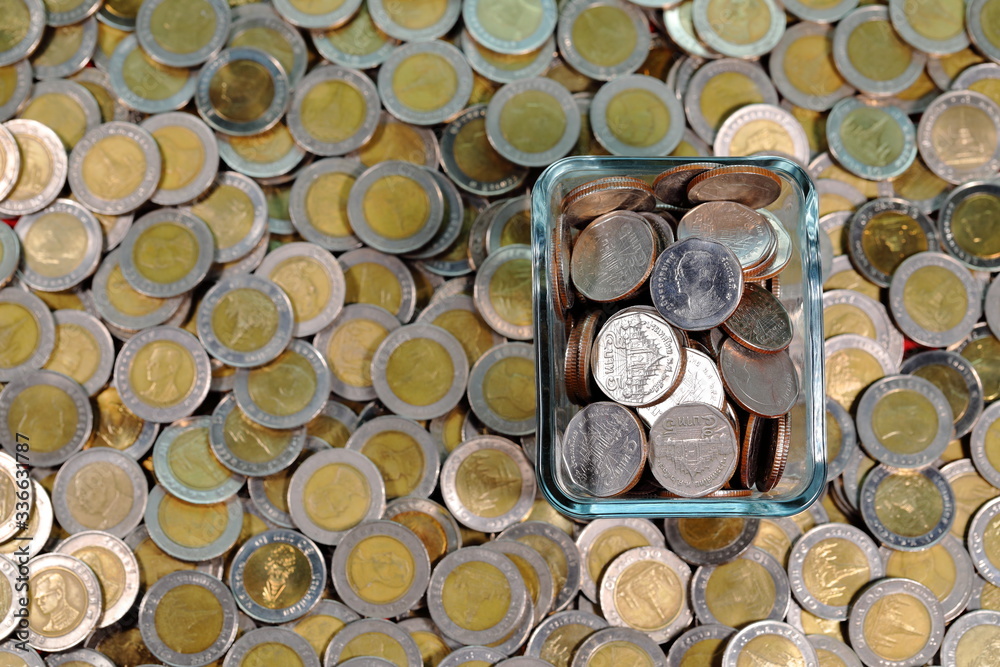 Thailand five baht coin in a cup Placed on a pile of ten baht coins ...