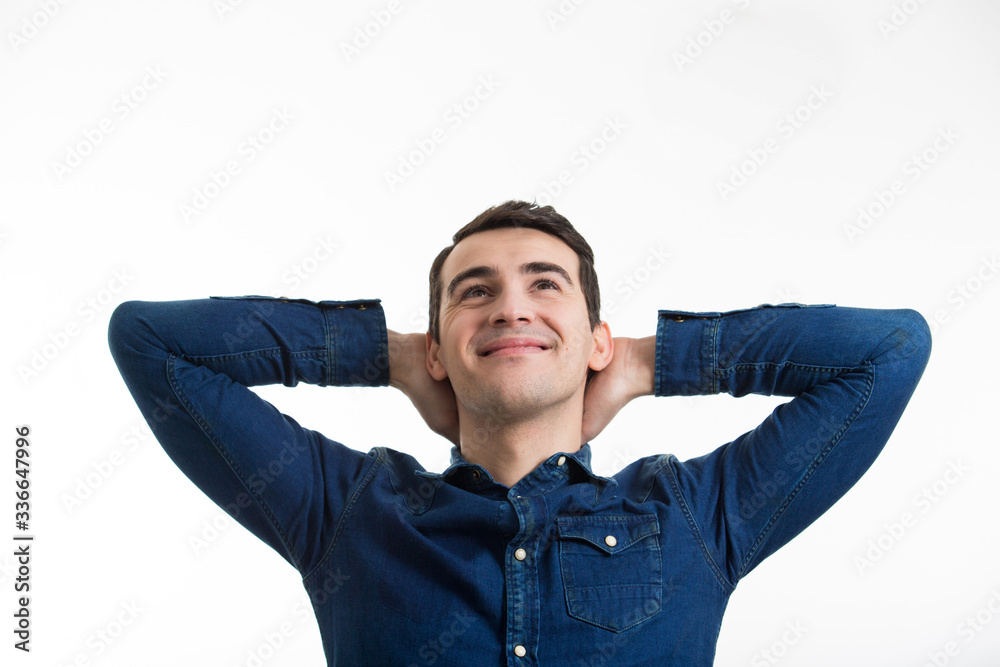Proud young man looking up with hands behind his had over white ...