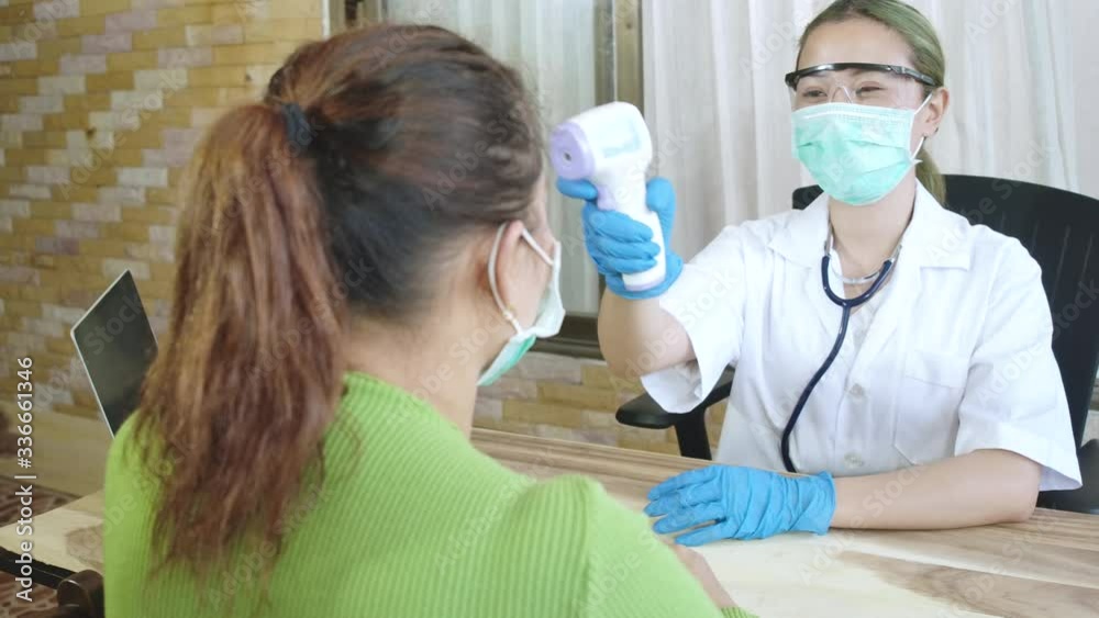 Female doctor checking temperature at patient with infrared tool in ...
