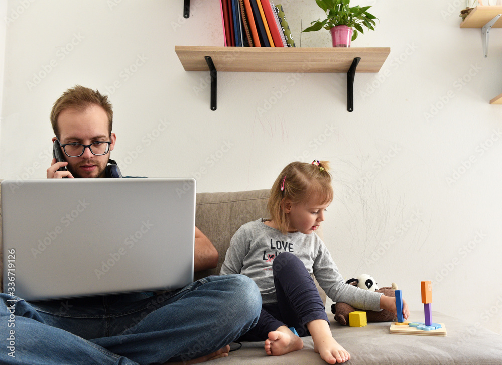 Dad working from home on his computer while his daughter is playing ...