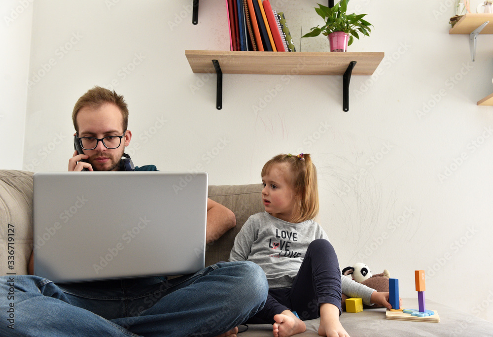 Foto de Dad working from home on his computer while his daughter is ...