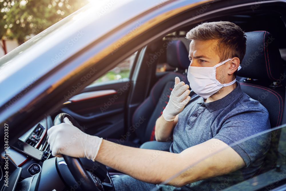 Man with protective mask and gloves driving a car having caugh ...