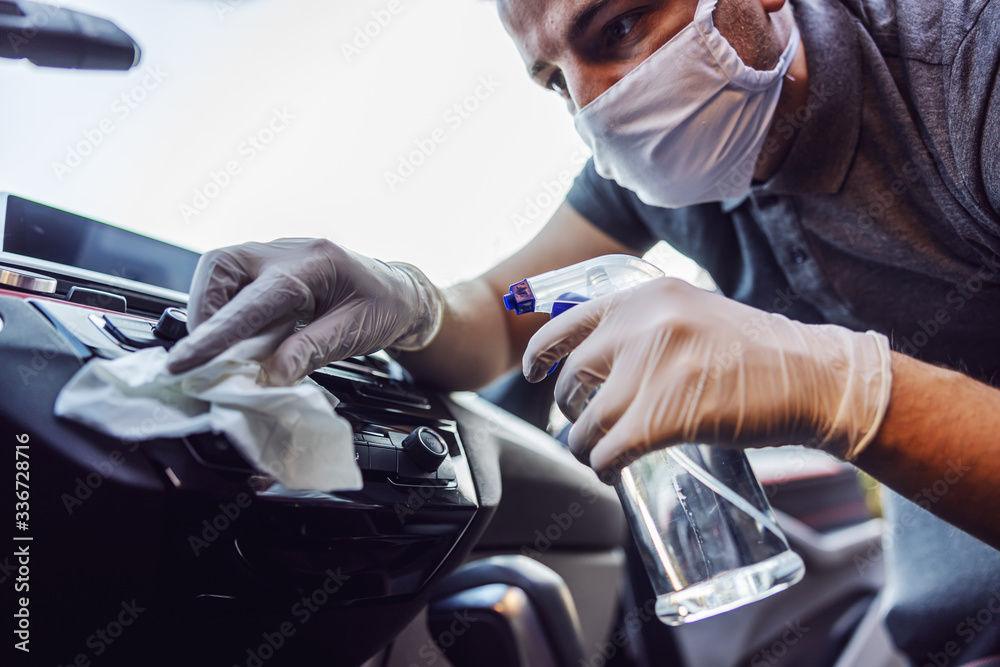 Man in protective suit with mask disinfecting inside car, wipe clean ...