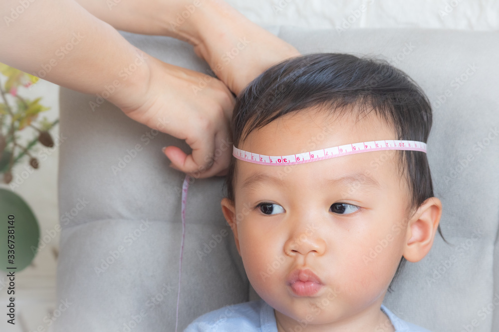 doctor measures the size of the head of a little boy,mother measures ...