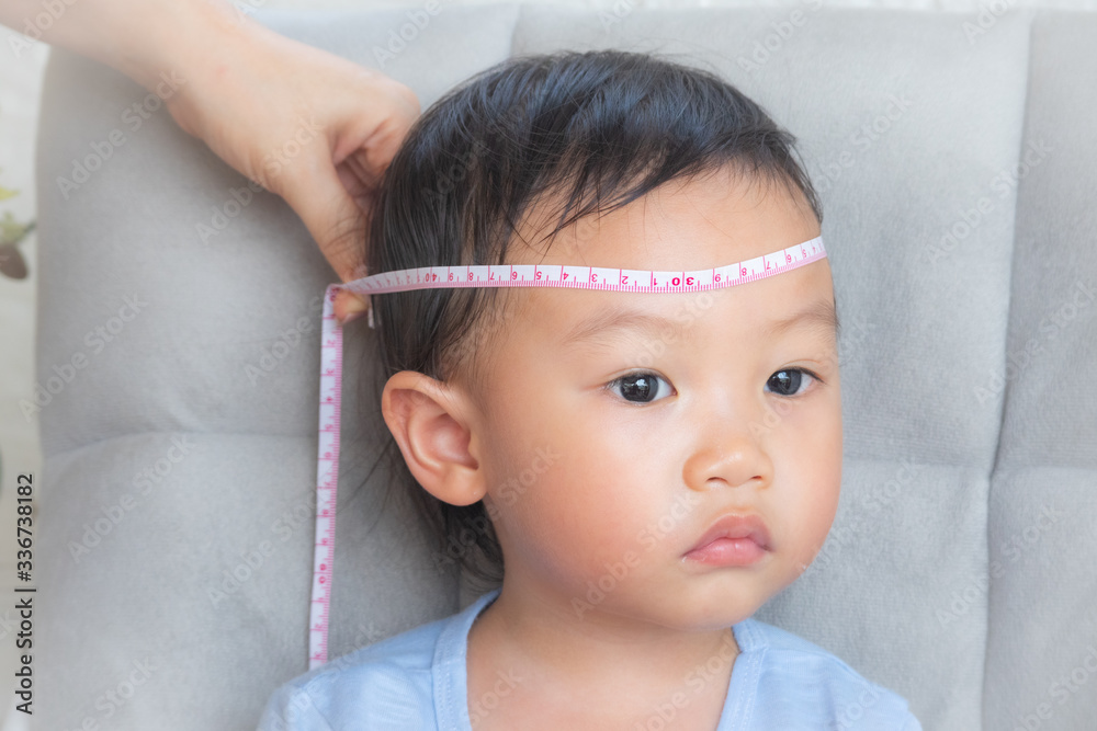 doctor measures the size of the head of a little boy,mother measures ...