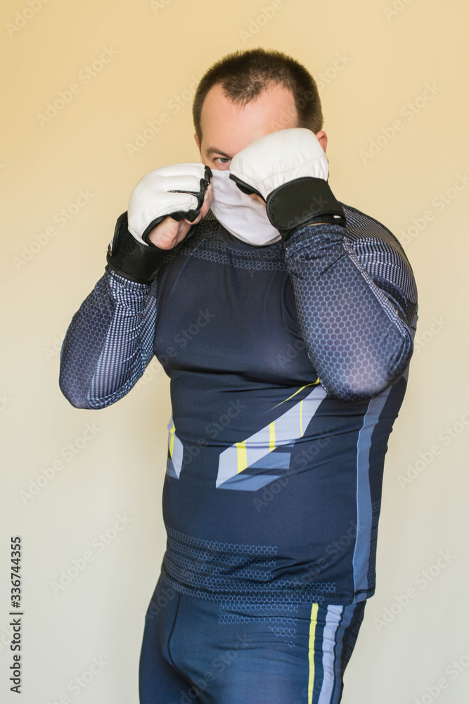 Strong young man boxing with a shadow in a mask on his face during a ...