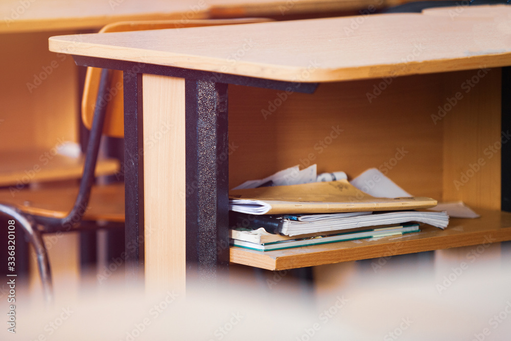 Closed school, books and notebooks left forgotten in a classroom desk ...