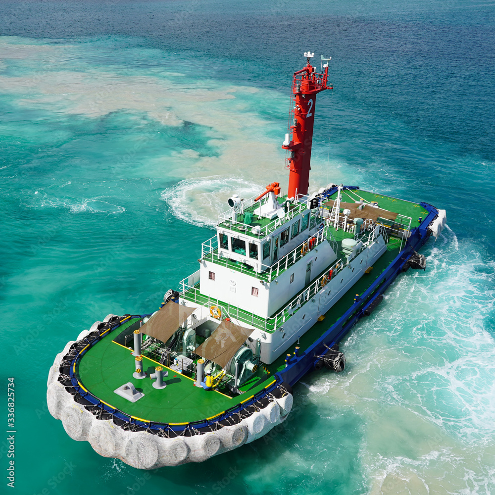 Colored tugboat works in port. bright tugboat in blue water. industrial ...