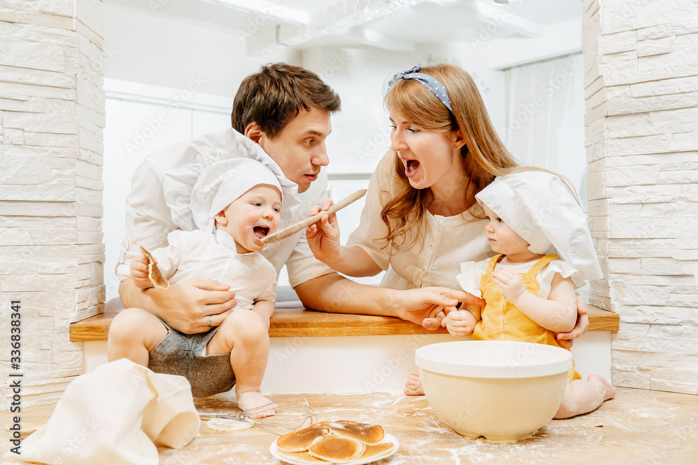 Caring cheerful caucasian mother feeds her little son with pie filling ...