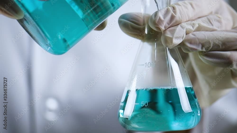 scientist hand holding a medical dropper filled with blue solution ...