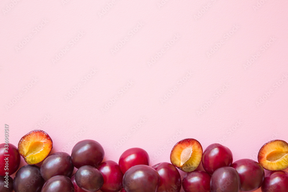 Beautiful, fresh whole and half of plums on light pink table background ...