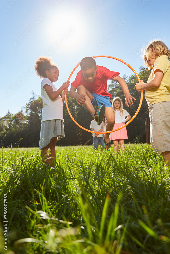 Kinder springen durch Reifen als Sport und Spiel Stock Photo | Adobe Stock
