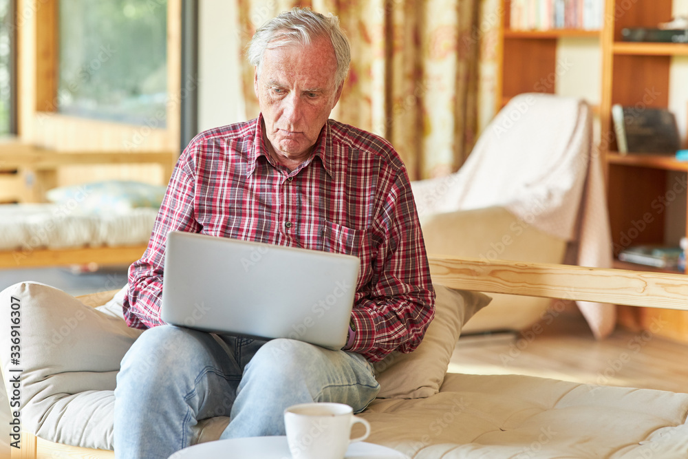 Senior with laptop computer online on the couch Stock Photo | Adobe Stock