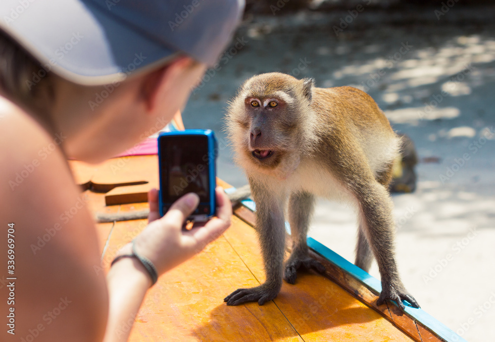 Girl takes a photo of monkey coming to a boat. Tourists take a photo ...
