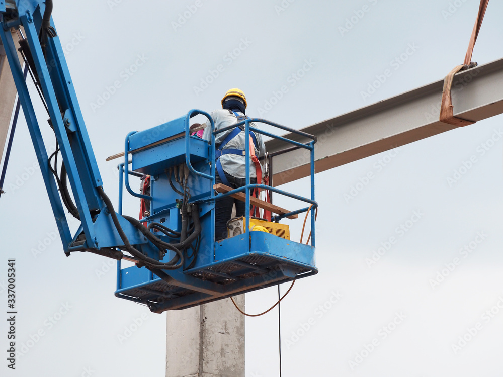 construction worker at construction site using lifting boom machinery ...