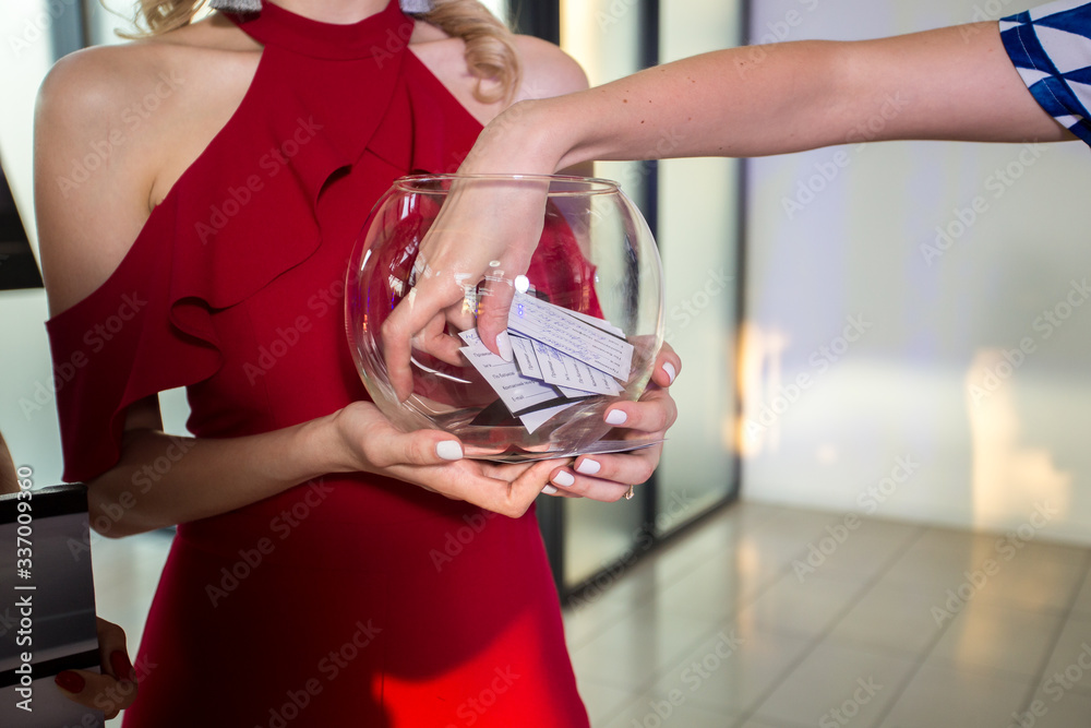 woman picking ticket with number from a glass bowl, random name ballot ...