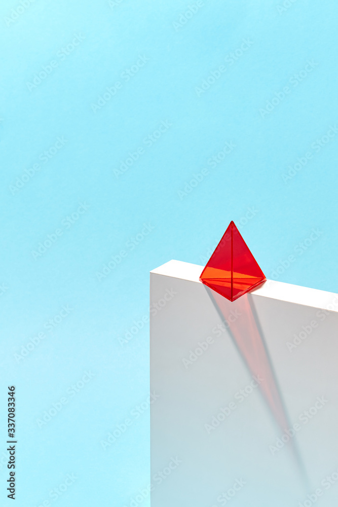 Red plastic pyramid on white box with shadow around blue background ...