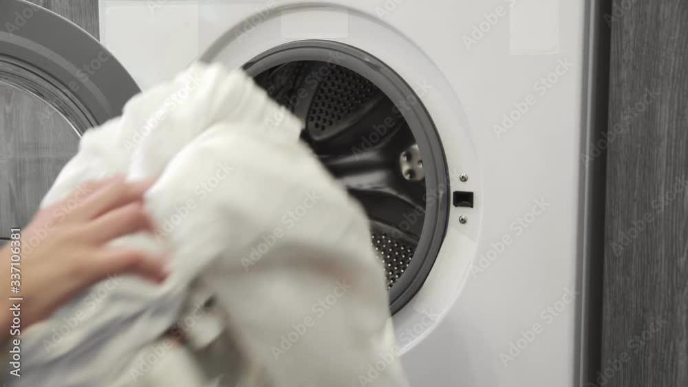 Female hand with married ring put WHITE CLOTHES in laundry machine ...