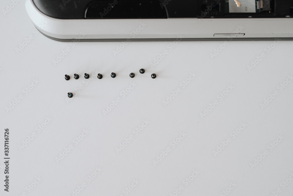 screws from a laptop stand next to the table. Disassembling a laptop ...