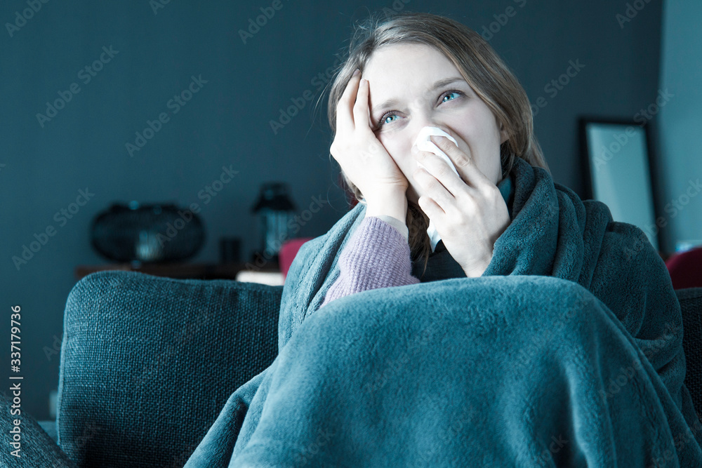 Bored sick young Caucasian woman covered with grey blanket sitting on ...