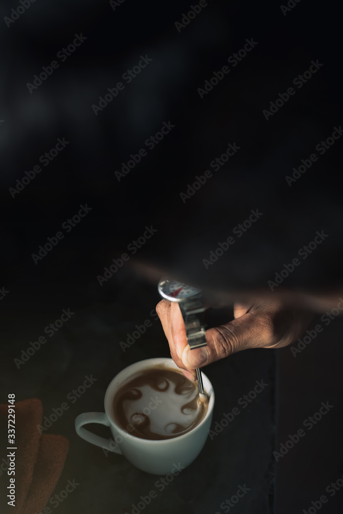 The barista's hand is drawing the pattern of the coffee. Soft focus ...
