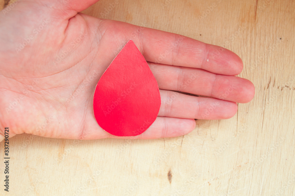 Hand holds a drop of blood. World Hemophilia Day. World Blood Donor Day ...