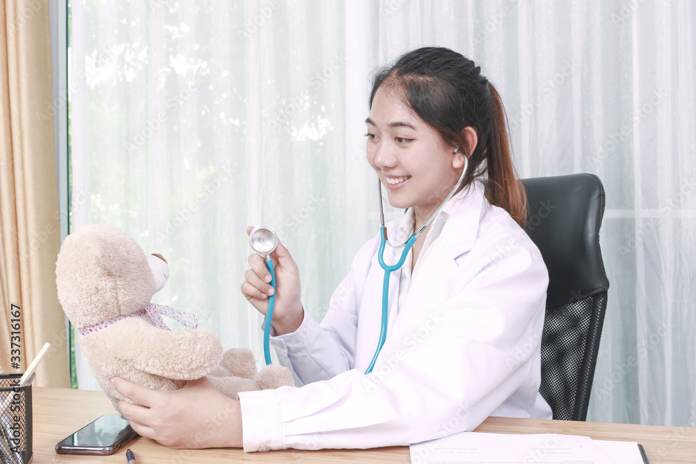 Smiling pretty Asian woman doctor setting in the hospital office, using ...
