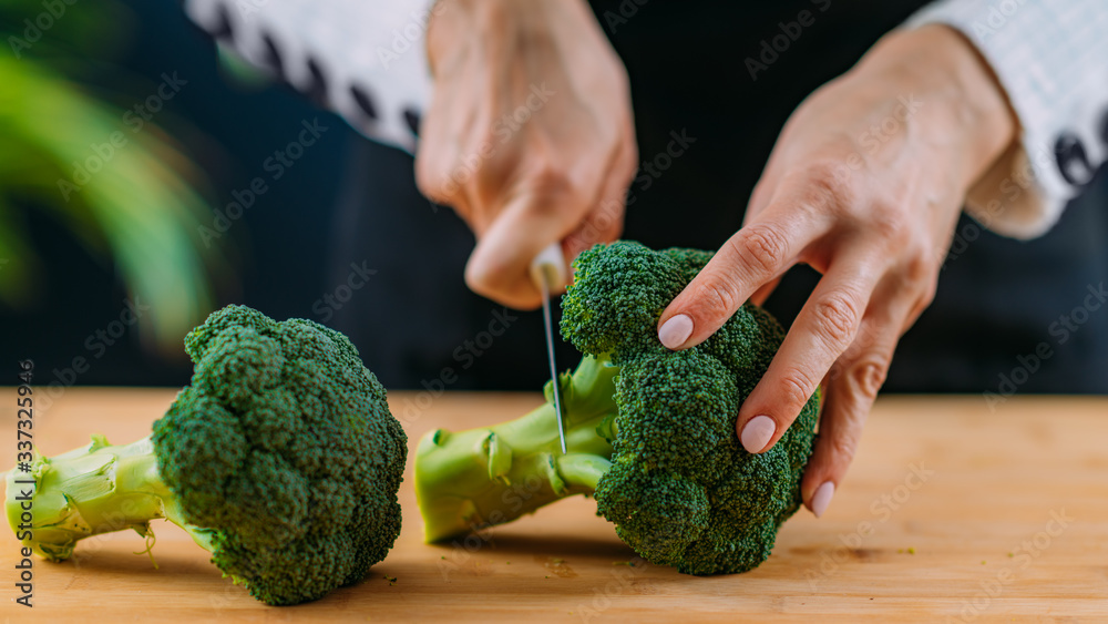 Cutting fresh organic broccoli, superfood rich in vitamin K, vitamin C ...