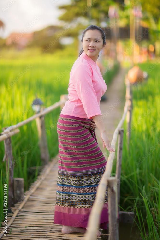 Beautiful Asian woman wear pink dress native cotton standing on bamboo ...