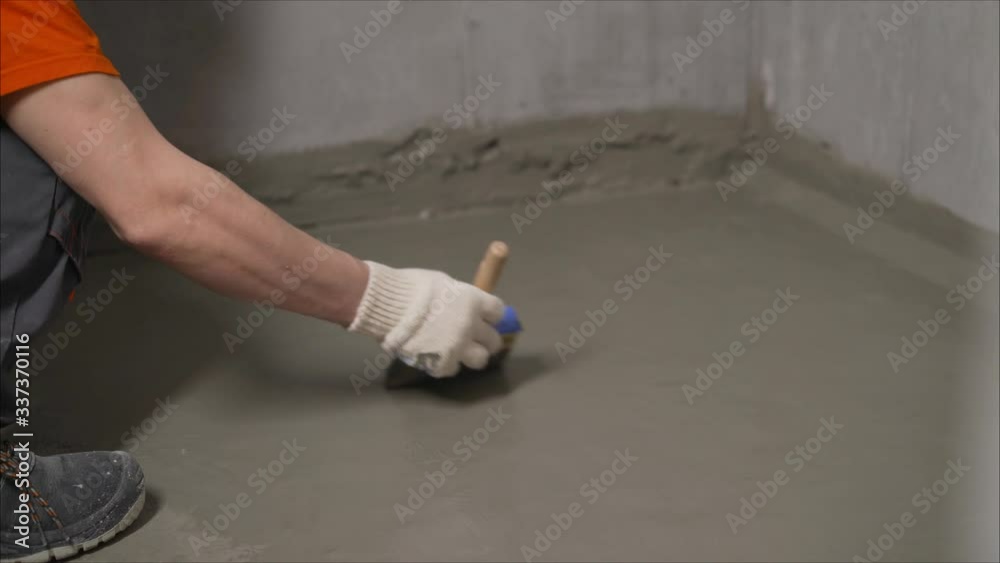 Workers cover the concrete screed with mortar and make waterproofing ...