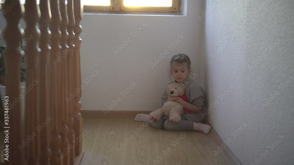 Abandoned child. Little girl beside the wall by the window alone with ...