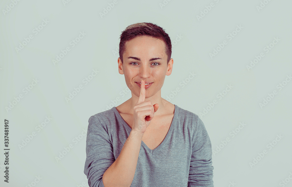 Closeup portrait happy young woman placing finger on lips asking shhhhh ...
