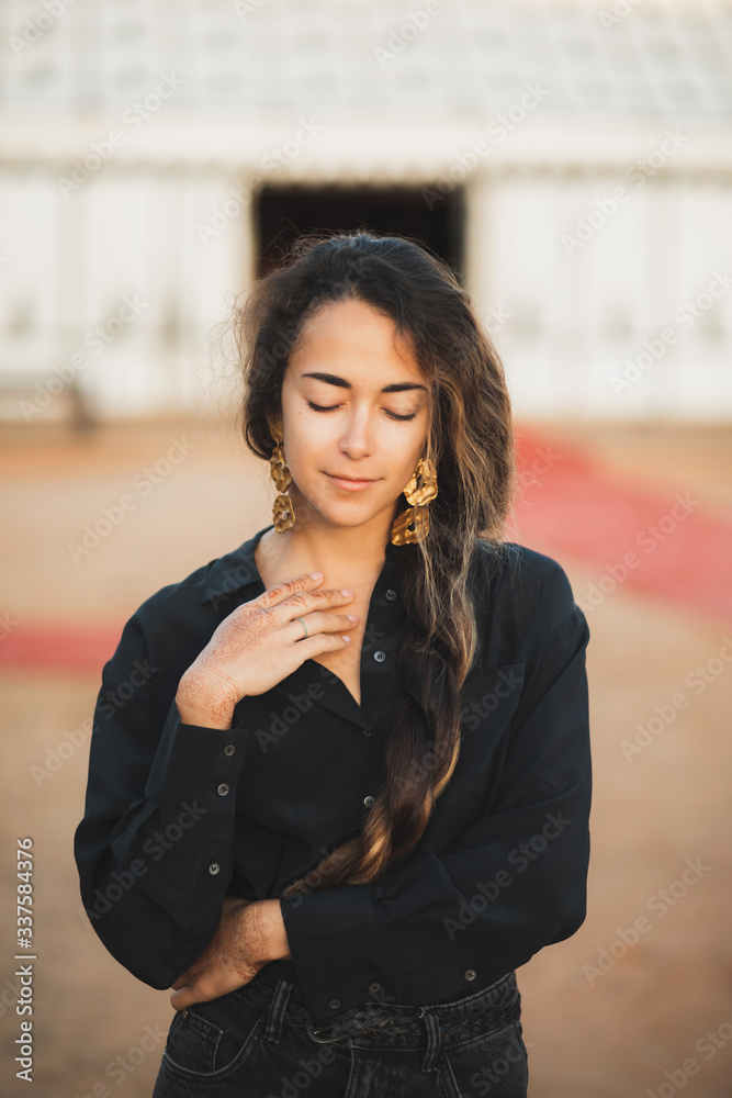 Close up glamour portrait of young oriental brunette woman with long curly hair and closed eyes ...