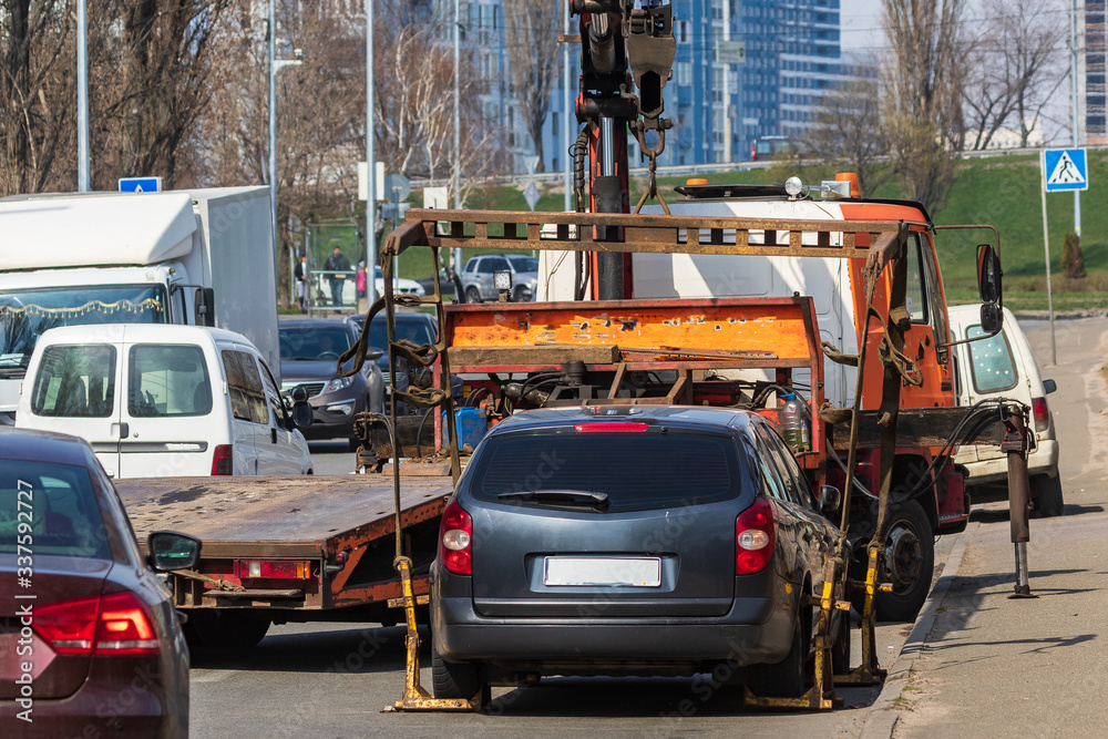 Loading a broken passenger car onto a yellow tow truck in the middle of ...