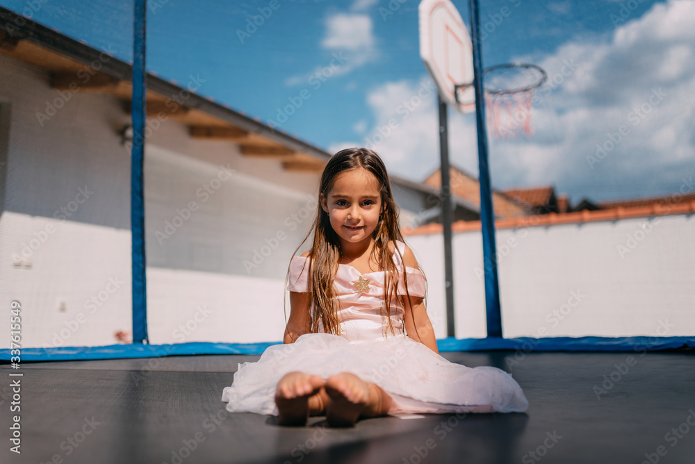 Little girl wearing princess costume sitting on trampoline Stock Photo ...