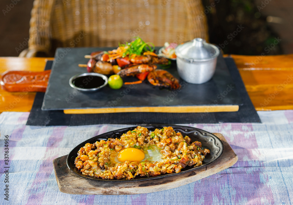 Sizzling pork sisig on the table with grilled shrimps, filipino cuisine ...