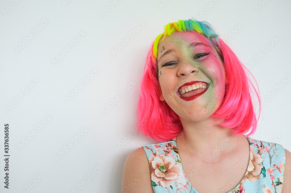 Teenage girl with a multi coloured wig and heavy make-up against a ...