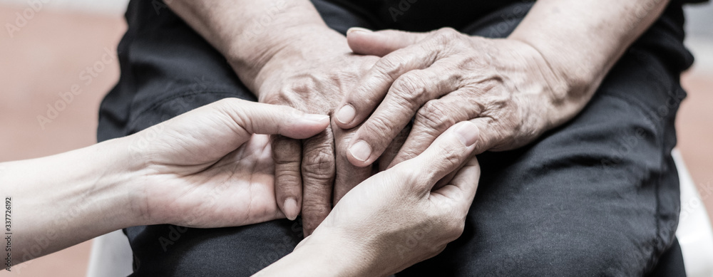 Caregiver, carer hand holding elder hand in hospice care background ...