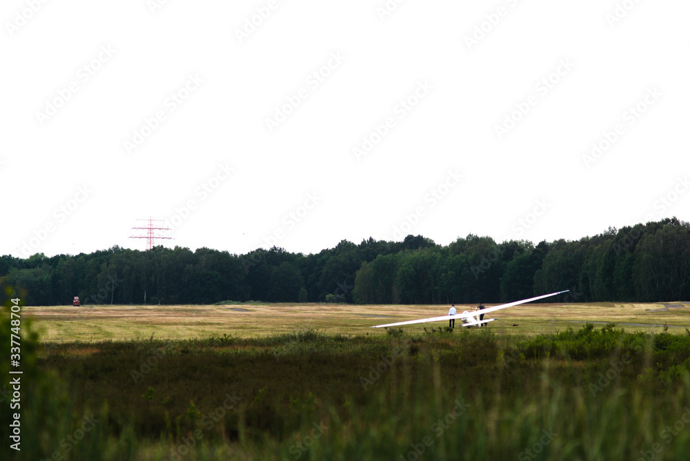 Segelflugzeug vor dem Start an einer Seilwinde vor Bäumen und Strommast ...