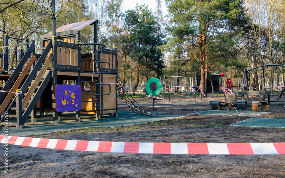 An empty playground, wrapped with a warning red and white tape, which ...