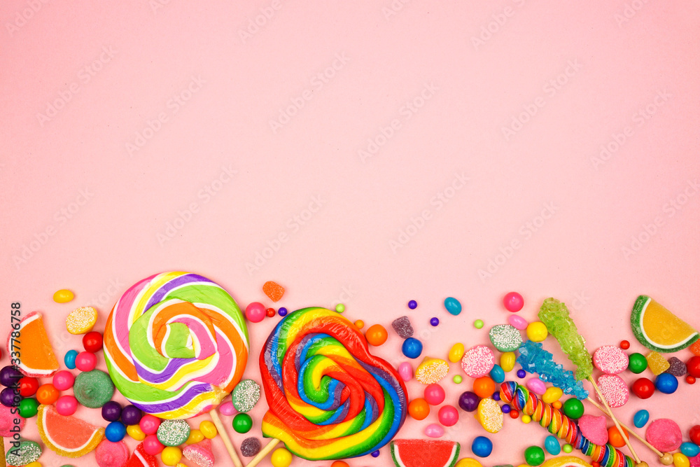 Colorful sweet candies. Above view bottom border on a pink background ...