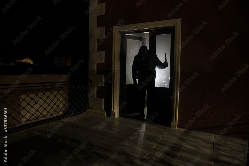 The silhouette of a human in front of a window at night. Scary scene ...