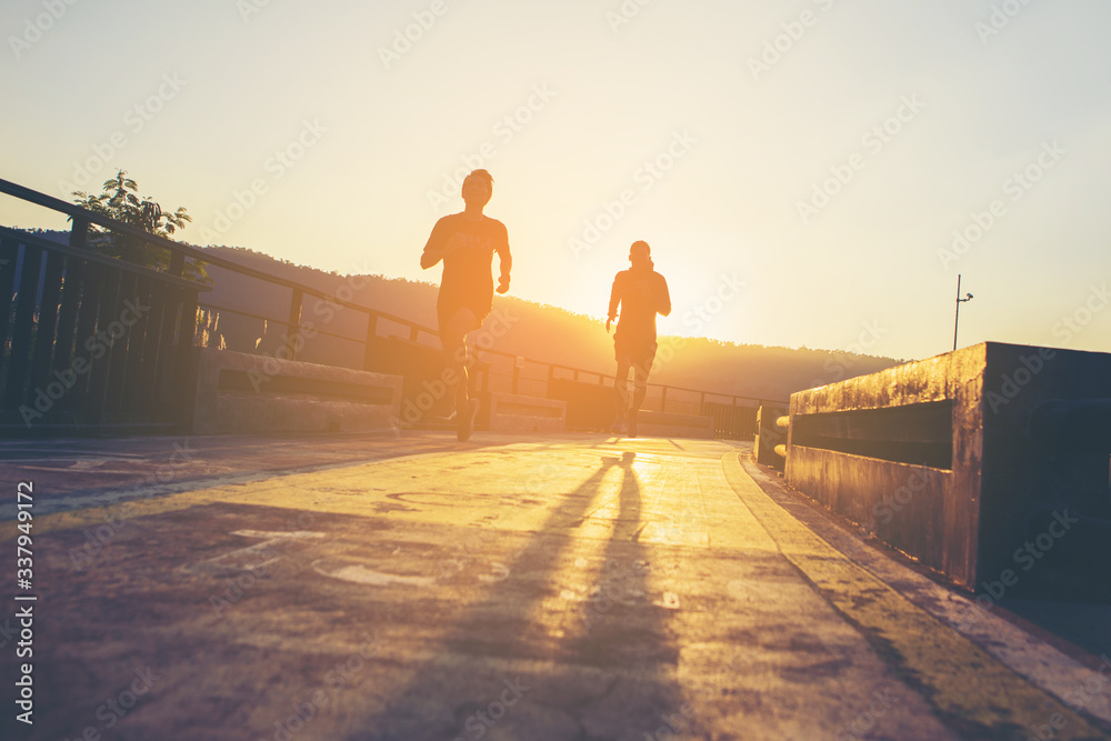 young people runner running on running road in city park at sunset ...